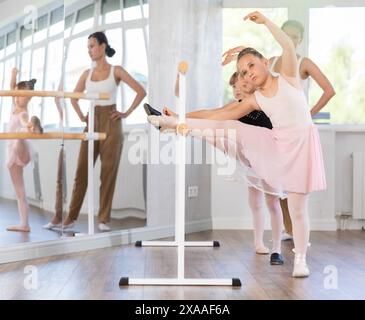 Little ballerinas together with choreography teacher in grand batman ...