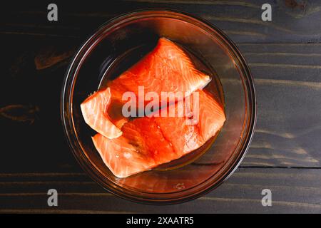 Raw fish fillets are in a glass dish with lemon and lime slices, carrot ...