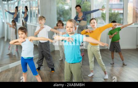 Energetic children practicing modern vigorous movements in dance class ...