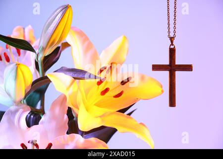 One cross with chain and beautiful lily flowers on purple background ...