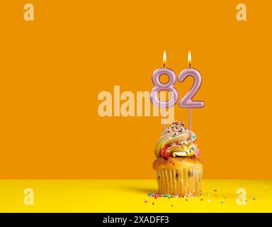 Lighted birthday candle number 82 - Birthday card on pink background ...