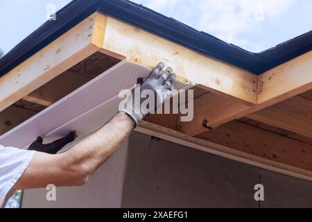 Installation of plastic vinyl soffit at ceiling corner on rafters ...