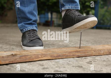 Careless man stepping on nail in wooden plank, closeup Stock Photo - Alamy