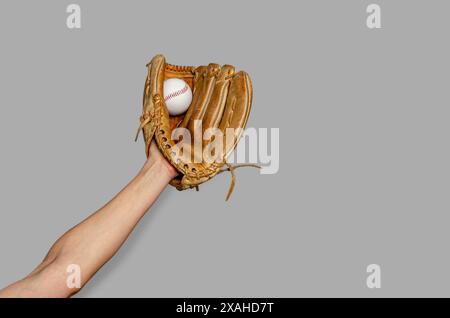 Female baseball gloved hand catches ball. Gray background. Active sport ...