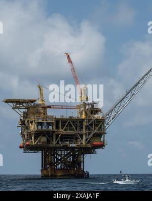 Anglers aboard a fishing boat target tuna near a large floating oil ...