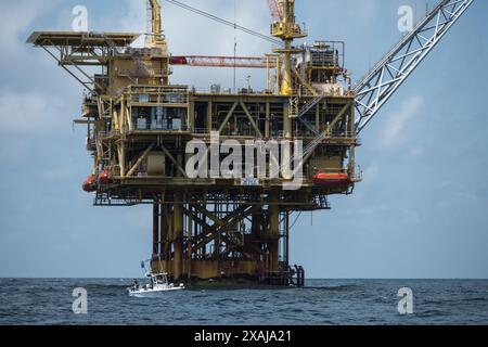 Anglers aboard a fishing boat target tuna near a large floating oil ...