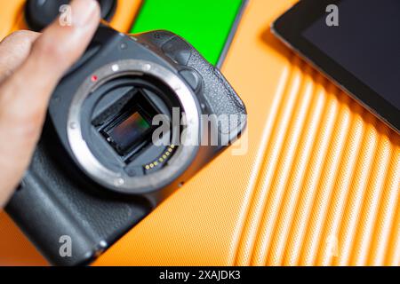A SLR camera without a lens next to a tablet on an orange surface Stock ...