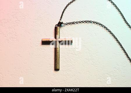 Cross with chain on textured table in color lights, top view. Religion ...