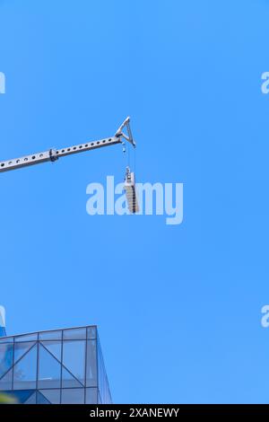 Crane lowering cleaning window equipment on high rise buildings, with ...