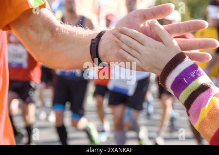 Marathon running race, supporting runners on road, child's hand giving ...