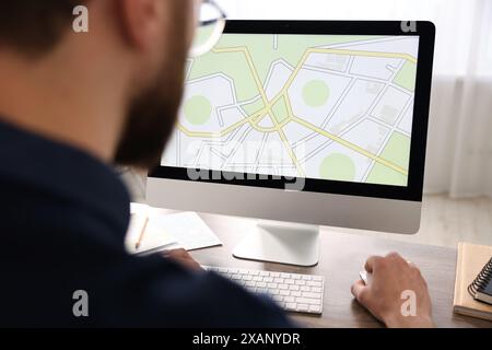 Cartographer working with cadastral map on laptop at white table in ...