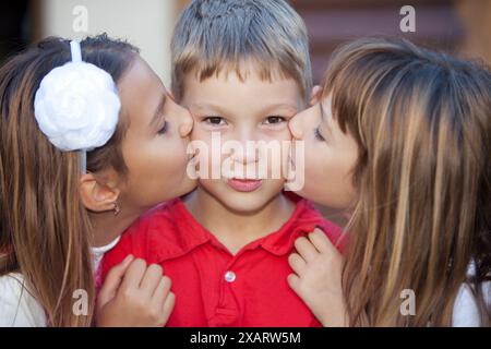 Two cute blond sisters kissing outdoors Stock Photo - Alamy