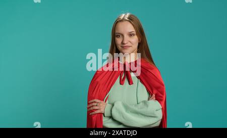 Smiling teenager portraying superhero wearing red cape, isolated over ...