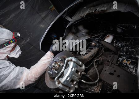 An auto mechanic applies anti-corrosion mastic to the underbody of a ...