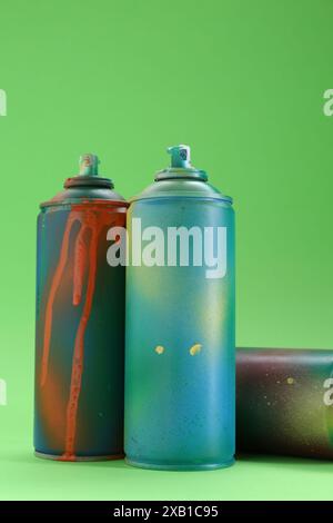 Spray paint cans on green background Stock Photo - Alamy
