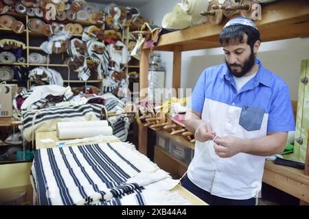 A religious Jewish man installing tzitzit on a prayer shawl in Crown ...