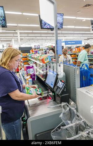 A female customer using self-checkout at Dollar General with her ...