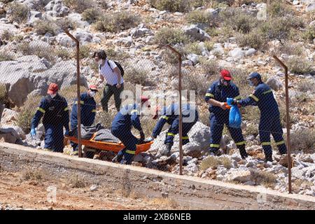 Greek Fire Services officers carrying away on a stretcher the body of ...