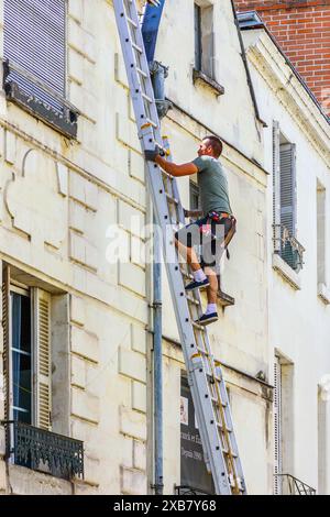 Workman (with no safety equipment) scaling tall rope-operated triple ...