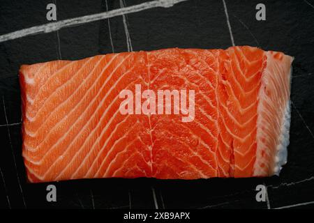 Vibrant orange salmon fillet on white ceramic plate with fresh green ...