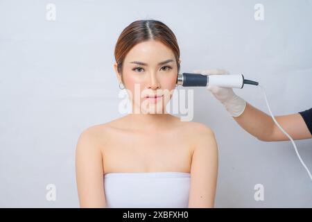 Beautiful Asian woman undergoing treatment with facial mask in beauty ...