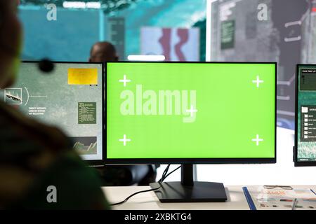Serviceman operates on surveillance footage and green screen display ...