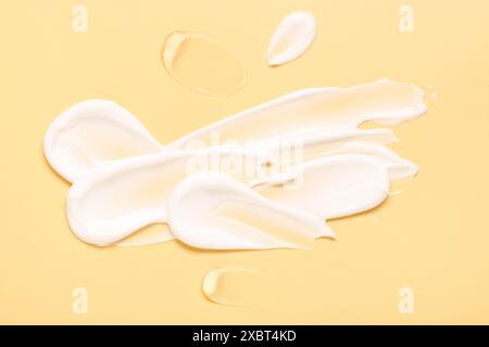 Samples of face cream on pale yellow background, top view. Space for ...