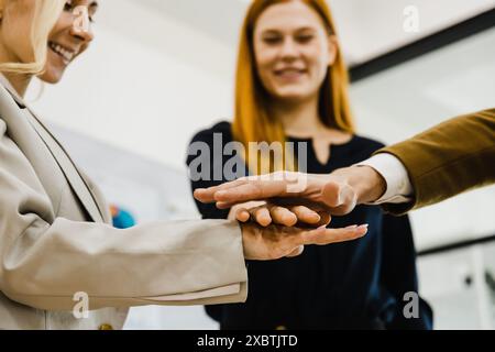 Multiethnic work team put their hands together as a sign of group union ...