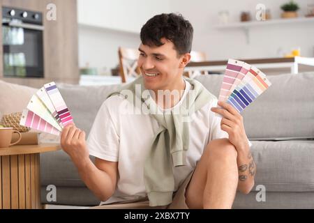 Young man with paint color palettes and shelf unit at home Stock Photo ...