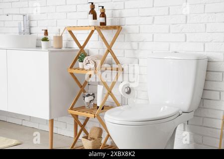 Interior of restroom with toilet bowl and shelving unit near blue wall ...