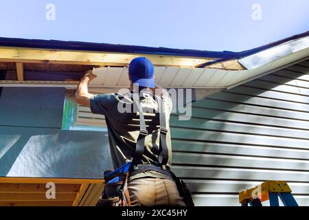 Mounting vinyl soffit plastic boards to roof rafters on ceiling house ...
