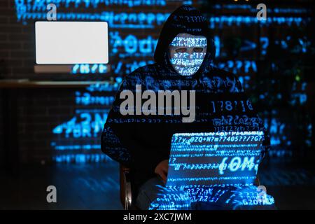 Hacker using laptop and projection of programming code in dark room ...
