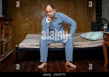 Grumpy old man in pajamas seated in an armchair isolated on white ...