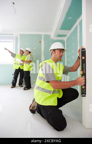 Worker with protective equipment, PPE, Leveling plasterboard panels ...