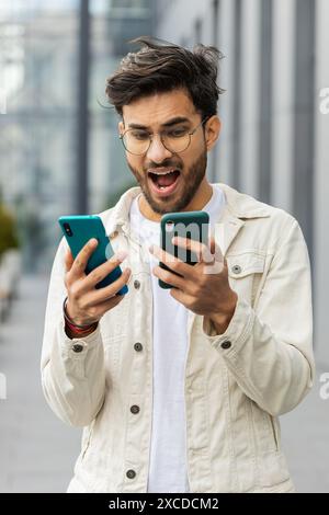 Irritated nervous stressed Indian man talking screaming on two mobile ...