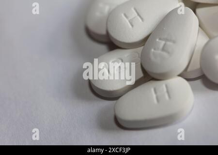 White pharmaceutical pills with numbers 123 and later h on back side ...