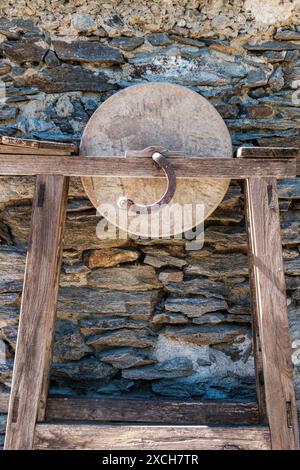 Old grindstone mounted on wooden frame with stone wall background Stock ...