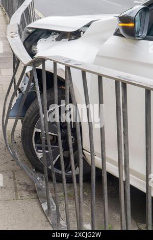 The front left wing of a white car that has crashed into railings ...