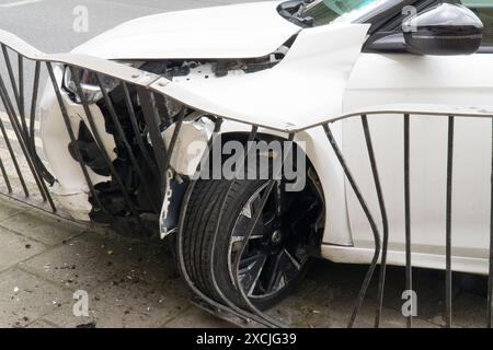 The front left wing of a white car that has crashed into railings ...