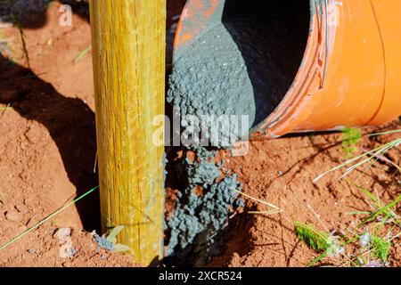 Pouring of concrete over newly installed timber fencing wooden fence ...