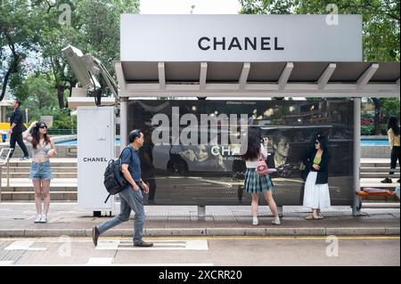 Commuters wait at a bus stop covered with French multinational clothing ...