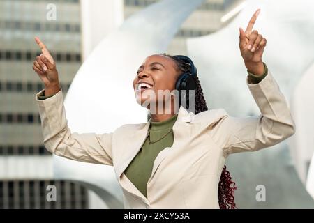 Happy Black woman enjoying music with headphones and smartphone ...