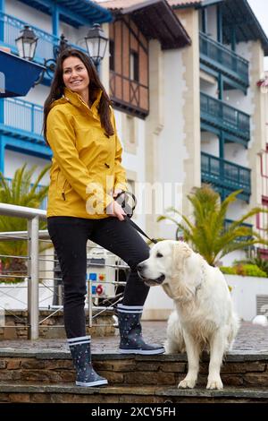 A person and a dog stand on coastal rocks looking out at the sea during ...