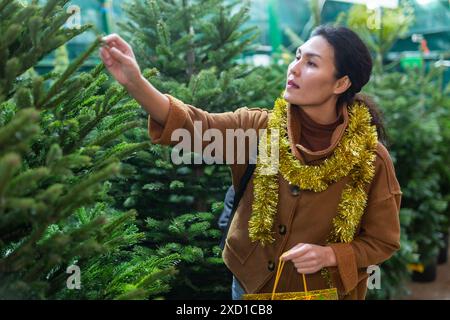 Happy asian woman chooses Christmas tree on street market Stock Photo ...