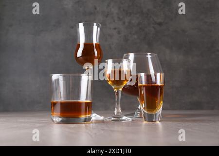Many different liqueurs in glasses on grey textured table Stock Photo ...