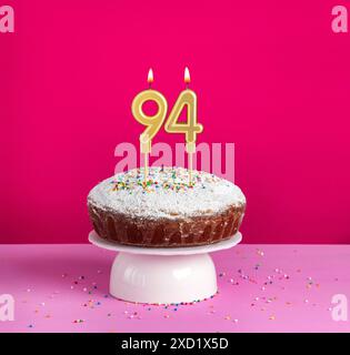 Pink number 94 birthday candle lit on white background Stock Photo - Alamy