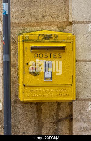 French yellow metal postal (la Poste) letter posting box on stone wall ...