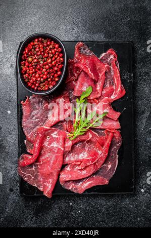 Slices of Beef Capriccio, raw marbled meat. Black background. Top view ...