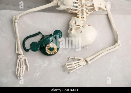 Waiting concept. Human skeleton at grey marble table with corded ...