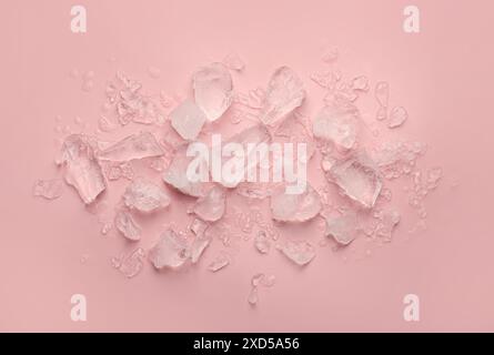 Pieces of crushed ice on pink background, top view. Space for text ...